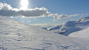 Paisagem montanhosa nevada sob um céu limpo e com luz do sol.