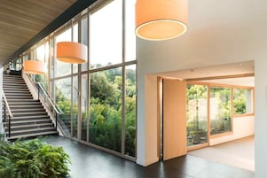 Um interior moderno com uma escada que leva a uma varanda, grandes janelas e design minimalista.