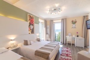 Quarto de hotel com uma cama grande, uma escrivaninha, uma cadeira e vista para o exterior.