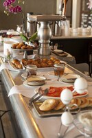 Uma mesa de buffet com diversos alimentos, incluindo doces, um pote de geleia e um frasco de mel.