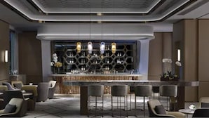 Uma área de bar moderna com uma luminária geométrica, balcão e assentos.
