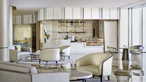 Um interior moderno com uma área de estar em curva, balcão de mármore com vitrine e um arranjo de plantas decorativas.