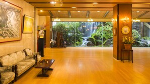 Um hall amplo com piso de madeira, um sofá, uma mesa de centro e uma grande janela com vista para uma cachoeira.