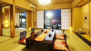 Um quarto japonês tradicional com tatames, uma mesa baixa e portas deslizantes.