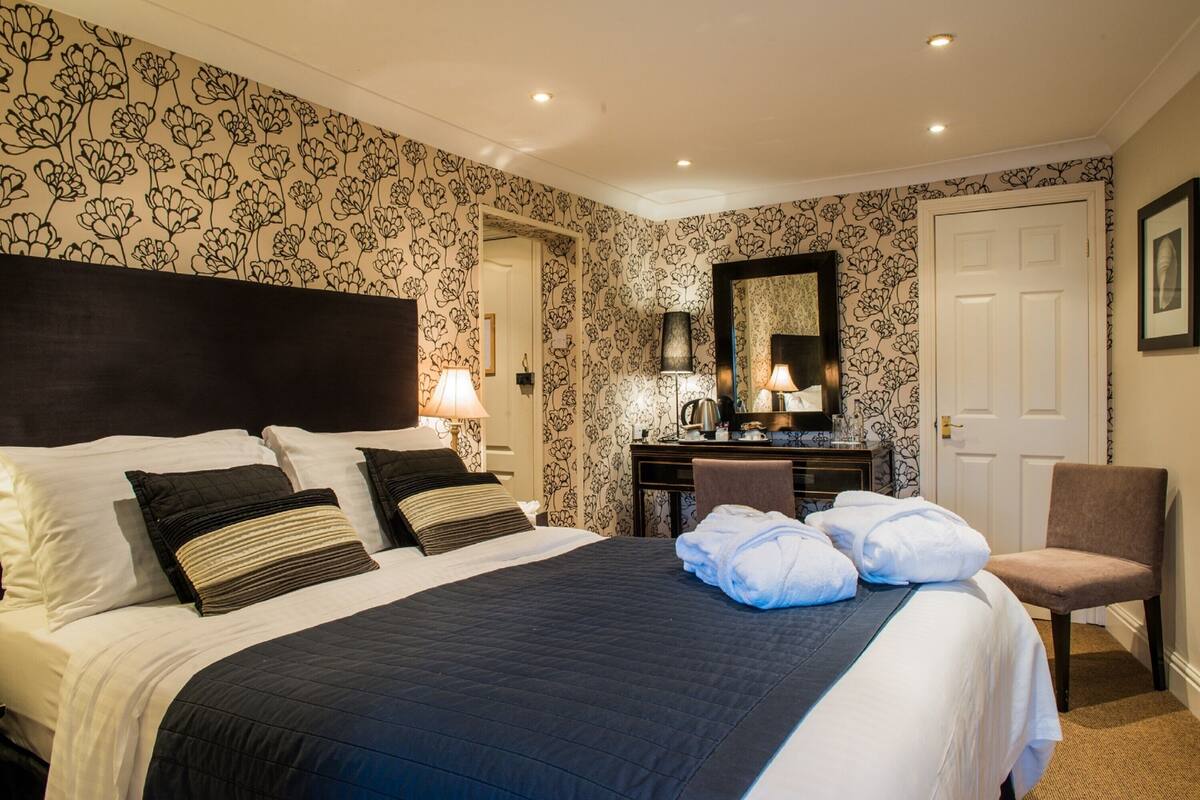 Quarto de hotel com uma cama grande, uma mesa, uma cadeira e um espelho.