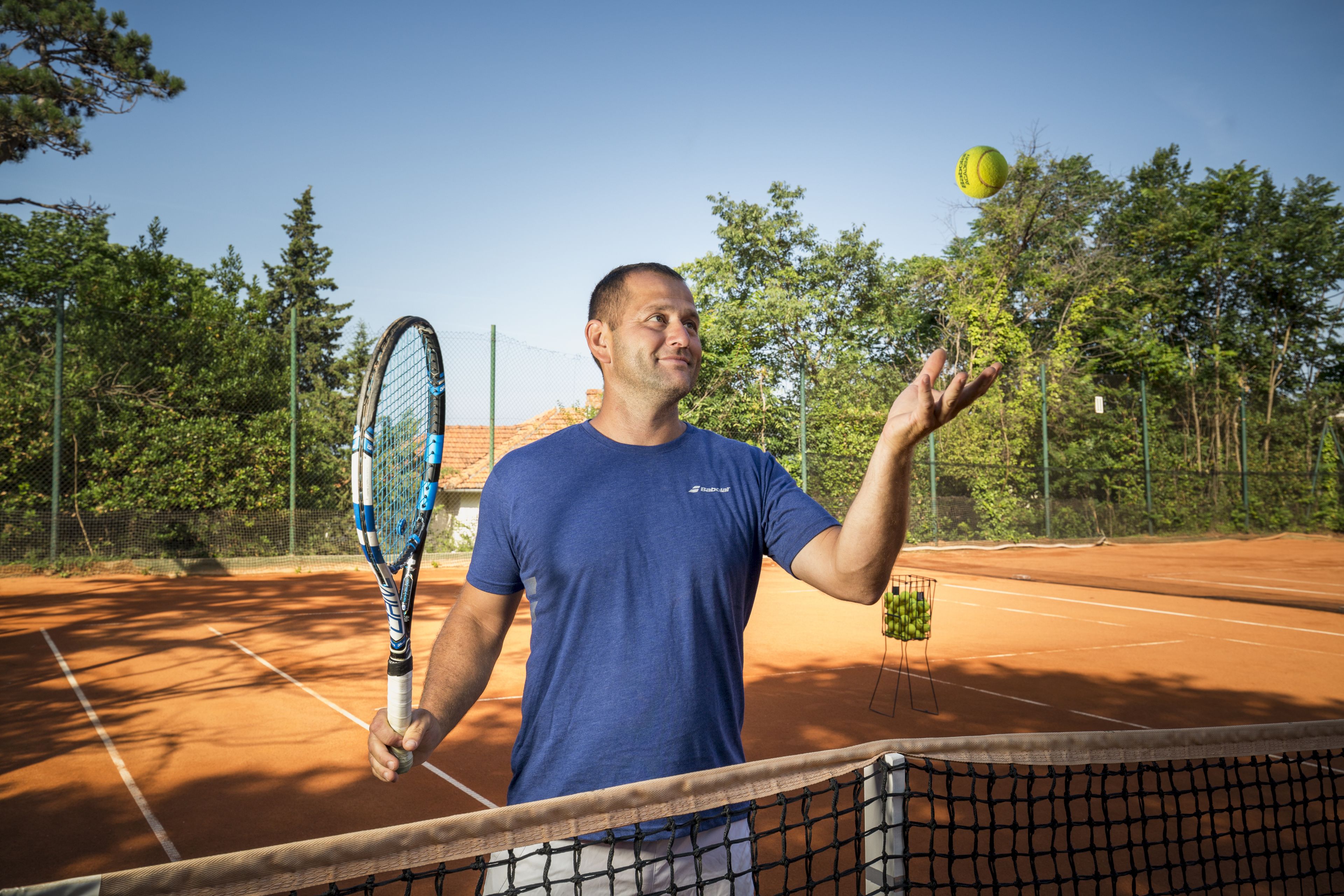 Uma quadra de tênis com rede, uma raquete de tênis e uma bola.