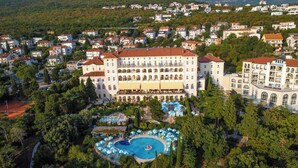 Um grande hotel com vários andares, piscina e área ajardinada ao redor.