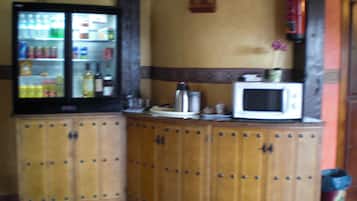Cozinha com armários de madeira, geladeira, micro-ondas e extintor de incêndio.
