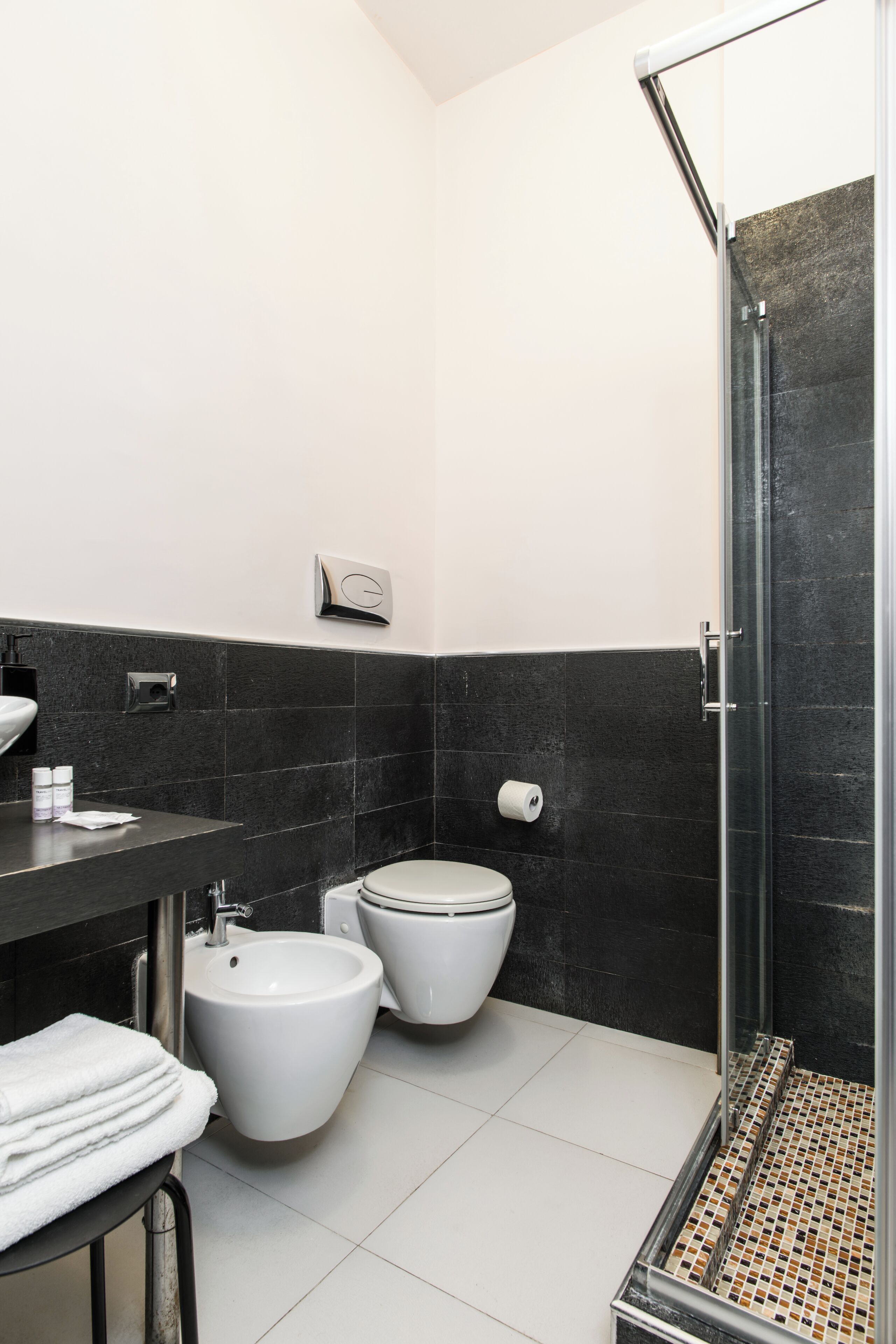 Um banheiro moderno com bidê, vaso sanitário e chuveiro com paredes de vidro.
