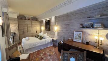 Quarto com cama, mesa de cabeceira, abajur e tapete estampado.