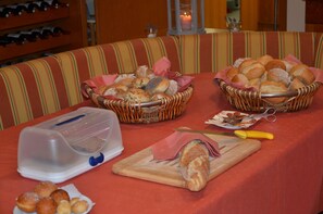 Uma mesa com cestos de pão, um pão numa tábua de corte e um recipiente de plástico.