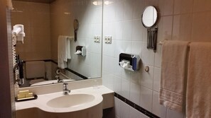 Uma casa de banho com lavatório, espelho, barra de toalhas e uma toalha pendurada na parede.