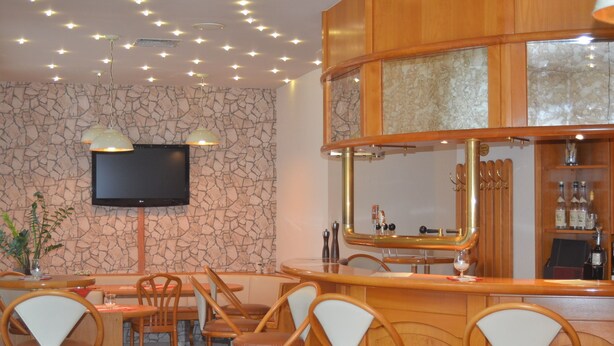 Um restaurante com parede de pedra, balcão de madeira e várias cadeiras.
