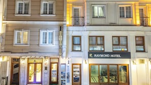 Um hotel de vários andares com uma placa chamativa que diz "Raymond Hotel".