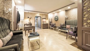 Uma sala de estar espaçosa com um sofá escuro, uma mesa de centro e um espaço de estar com poltronas e um sofá.