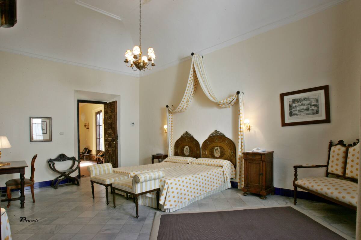 Um quarto tradicional com uma cama de dossel, duas mesas de cabeceira, um armário de madeira e uma cadeira.