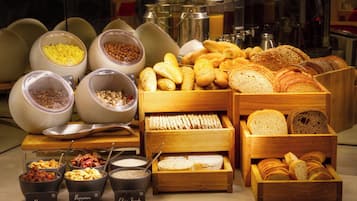 Um buffet de café da manhã com diversos alimentos e pães.