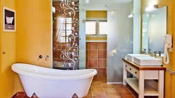 Um banheiro com banheira de pés livre, toucador com espelho e área de chuveiro com porta de vidro.