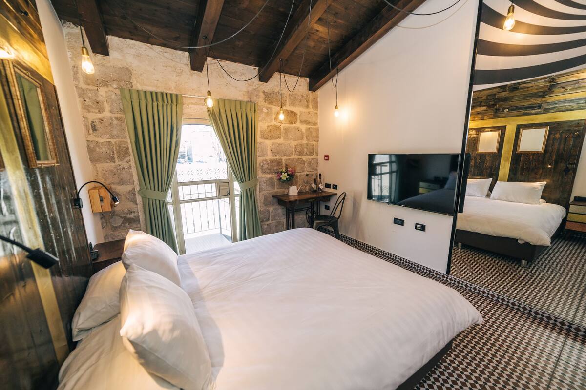 Quarto com uma cama grande, um espelho, uma televisão e uma parede de pedra.