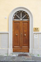 Uma porta dupla de madeira com uma grade de metal, um letreiro com o número '2' acima dela e uma placa com a inscrição 'B&B IL SEMINARIO'.