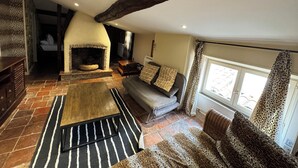 Uma sala de estar acolhedora com lareira, um sofá, uma mesa de centro e uma janela com cortinas.