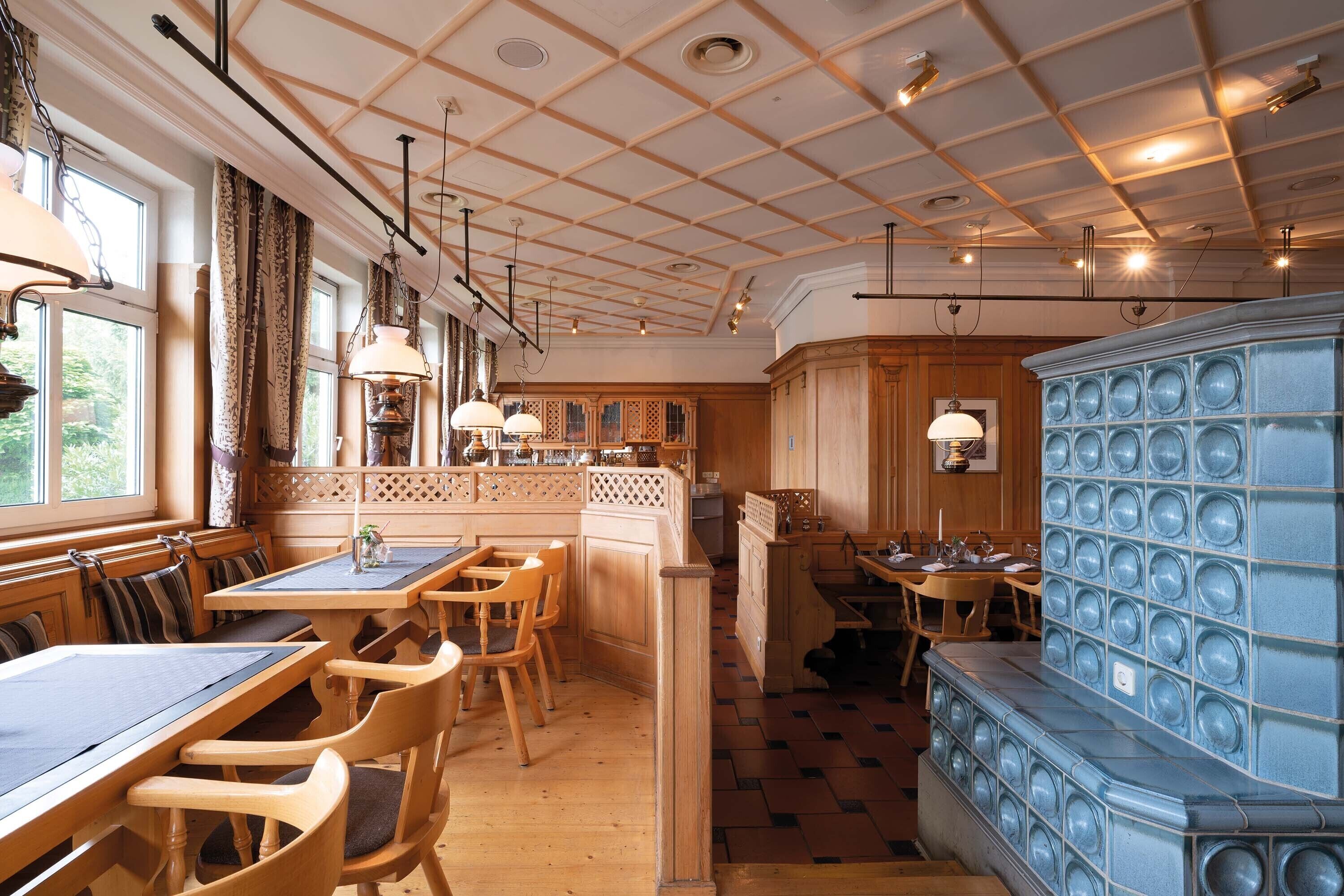 Um restaurante com mesas e cadeiras de madeira, uma ilha central com azulejos azuis e um teto com padrão de grade.