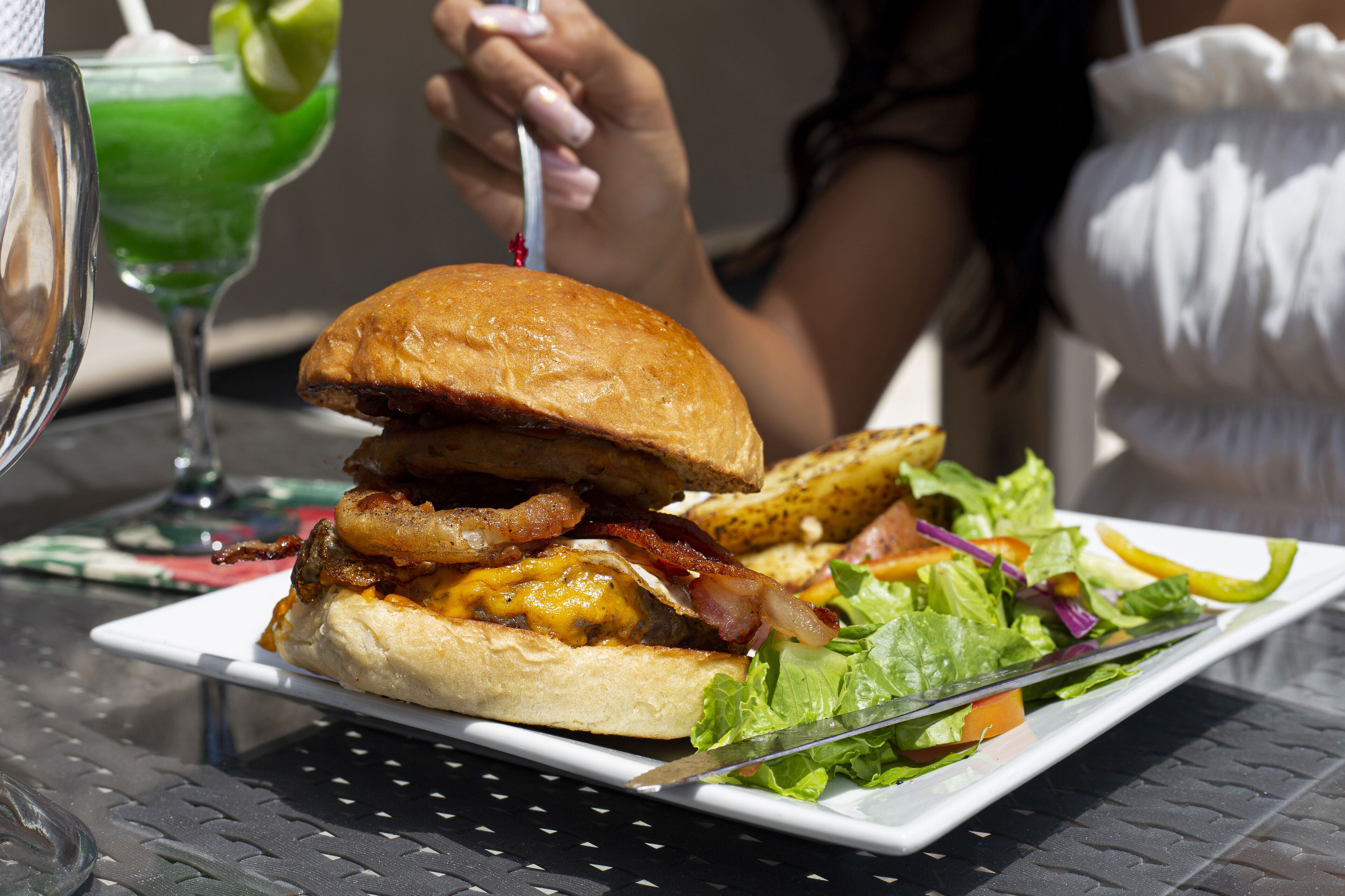 Sanduíche com bacon, queijo e alface sobre um prato branco.