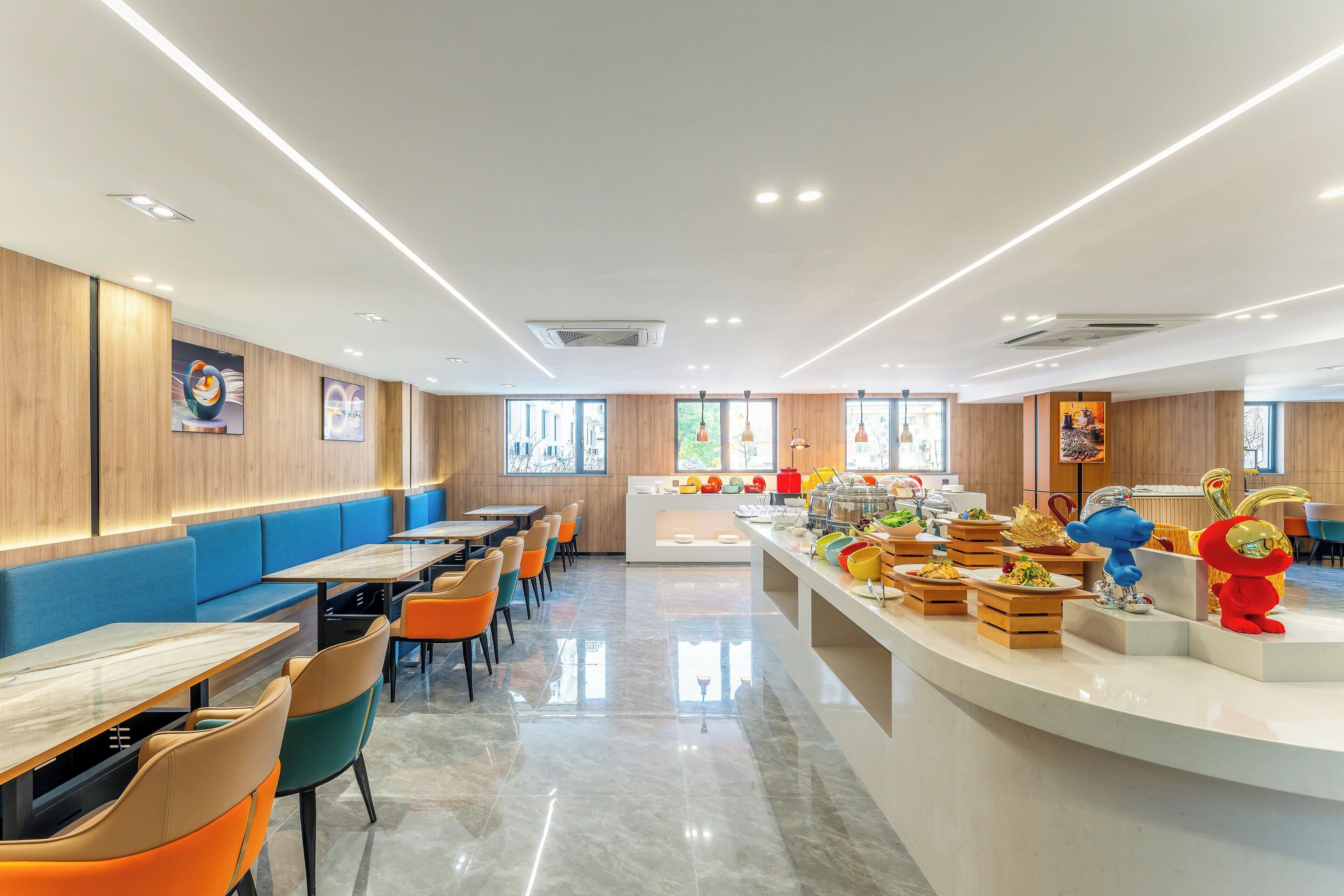 Restaurante moderno com buffet central, área de estar com mesas e cadeiras e paredes de painel de madeira.