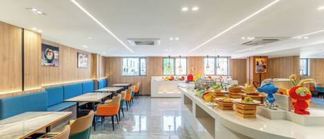 Restaurante moderno com buffet central, área de estar com mesas e cadeiras e paredes de painel de madeira.