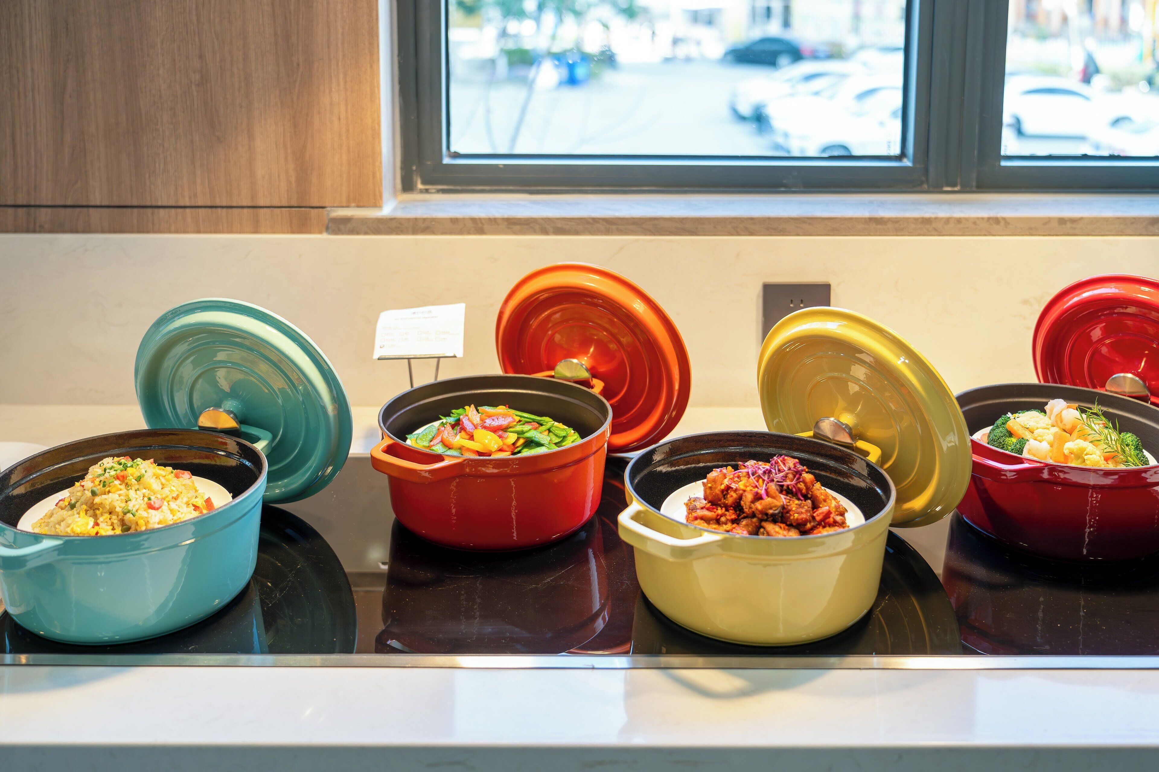 Uma bancada de cozinha com vários panelas coloridas contendo diferentes pratos.