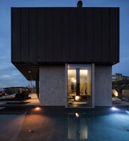 Um edifício moderno com piscina, área de estar ao ar livre e lareira visível.