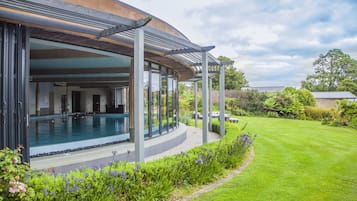 Um edifício moderno com piscina, varanda coberta e um jardim bem cuidado.