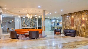 Um lobby moderno com área de estar em curva, balcão de recepção e um painel decorativo.