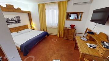 Quarto de hotel com cama, escrivaninha de madeira, televisão e espelho.