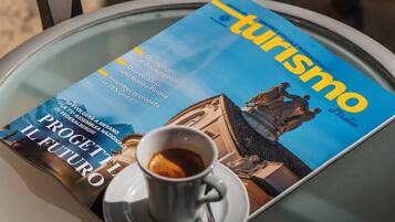 Uma mesa de vidro com uma revista, uma chávena de café e uma colher.