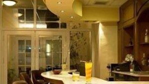 Uma cozinha moderna com uma ilha curva, banquetas de bar e uma porta de vidro que dá para uma sala de jantar.