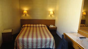 Quarto de hotel com cama, abajures, mesa de cabeceira, escrivaninha e espelho.
