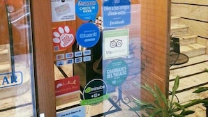 Parede de vidro com diversos adesivos divulgando serviços e comodidades, como Google, Foursquare e TripAdvisor.