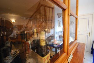 Quarto com escada de madeira, vitrine de vidro com vários frascos e porta com placa.