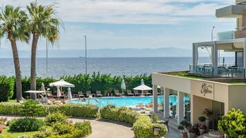 Um resort com piscina, palmeiras e vista para o mar.