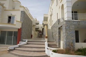 Edifício residencial com escadaria central, fachada de pedra e várias sacadas.
