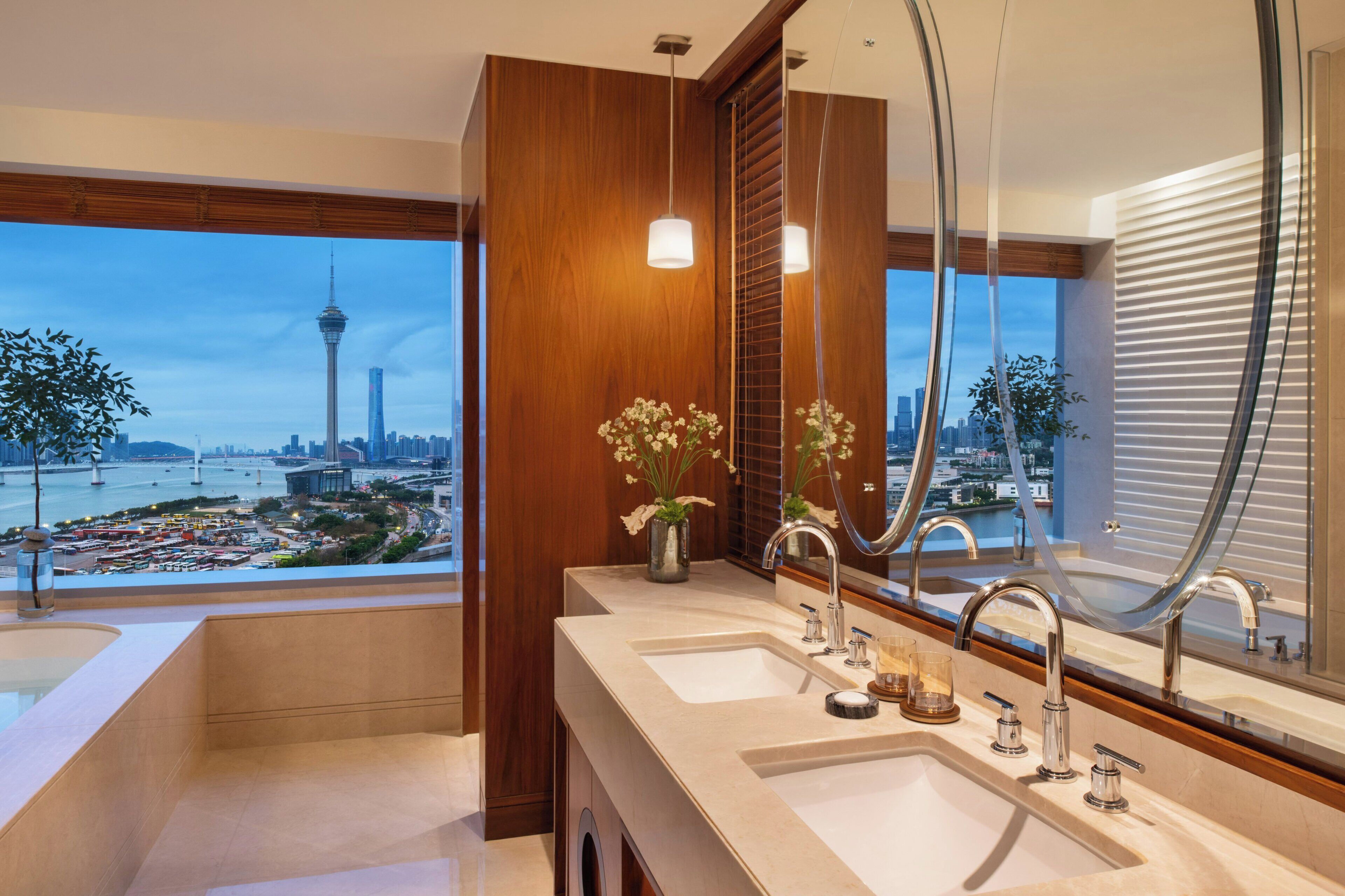 Uma casa de banho moderna com duas pias, um espelho grande e vista para a cidade, incluindo uma torre.
