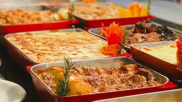 Buffet com diversos pratos, incluindo um ensopado, um prato de carne e uma sobremesa.