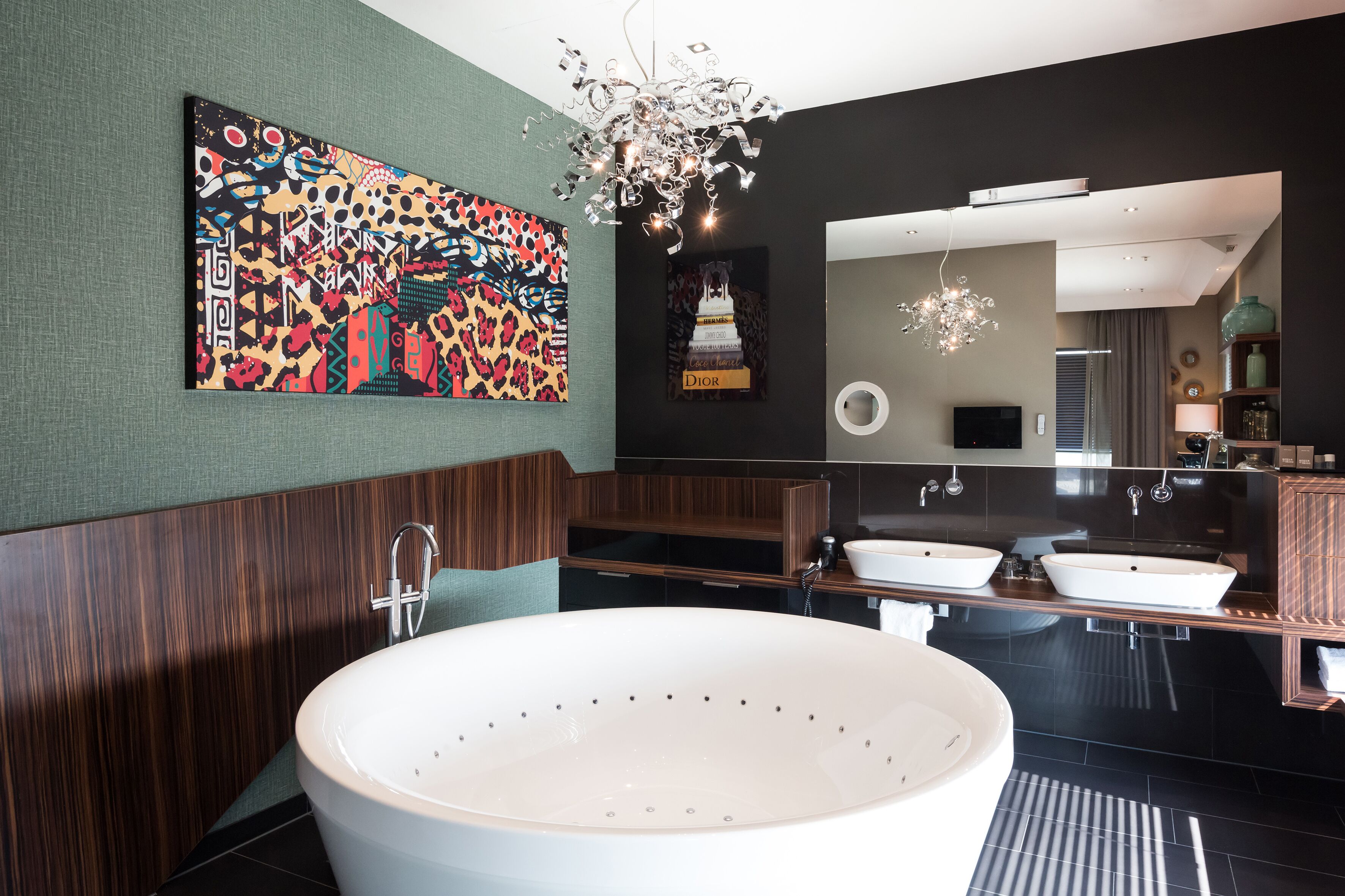Uma casa de banho moderna com uma banheira grande independente, duas pias, um espelho e um candeeiro decorativo.