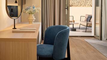 Quarto moderno com escrivaninha de madeira, cadeira azul, espelho e um vaso com flores.