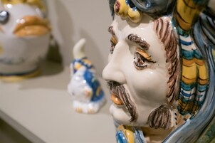 Close-up de uma miniatura de cerâmica com rosto detalhado e padrão colorido listrado no corpo.