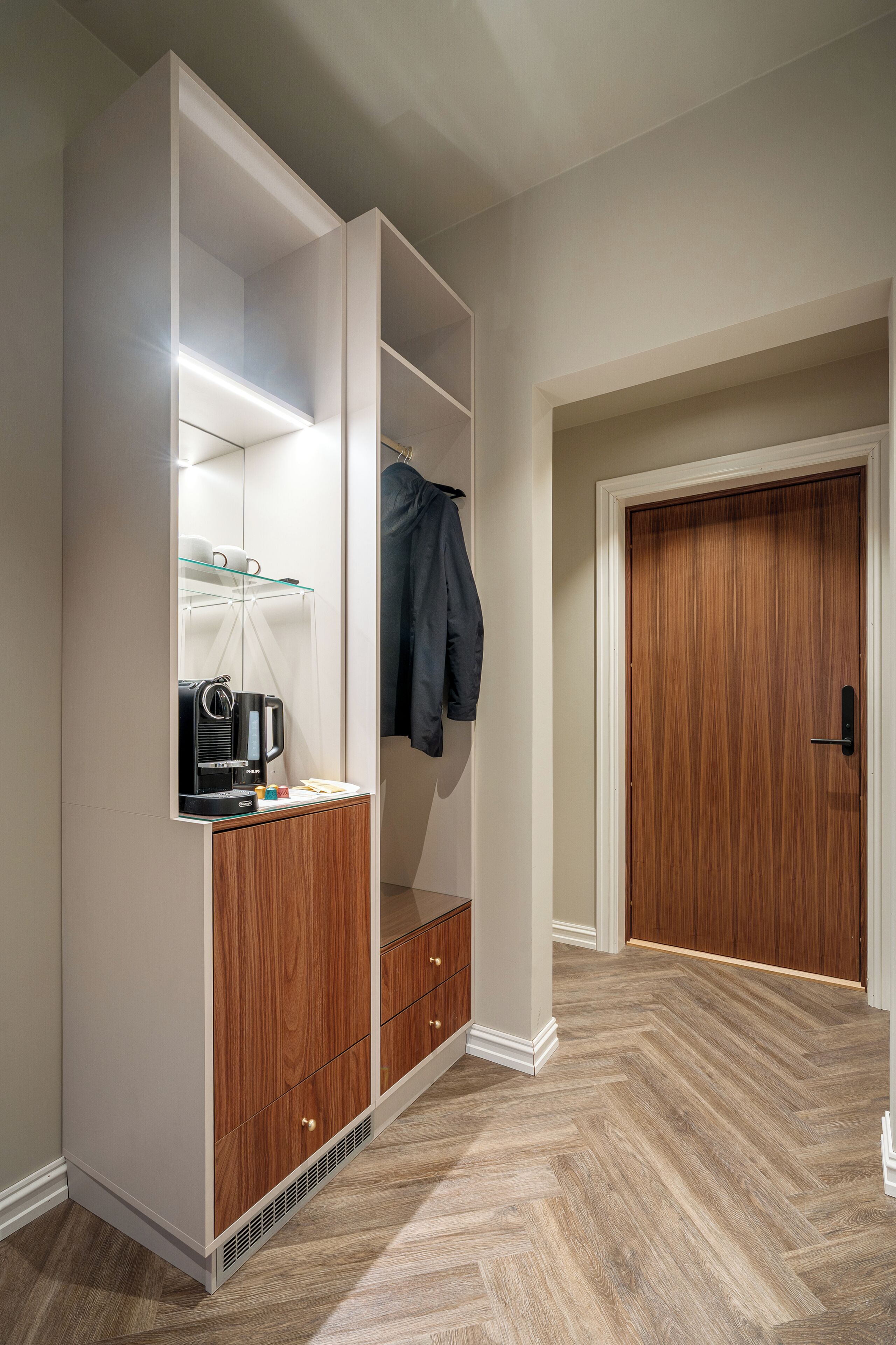 Um corredor com um guarda-roupa, um cabideiro e uma porta de madeira.