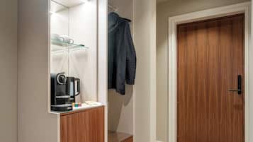 Um corredor com um guarda-roupa, um cabideiro e uma porta de madeira.