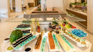 Buffet com diversos alimentos e um arranjo central decorativo em formato de árvore.