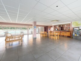 Um hall amplo com vista para a piscina, mobiliário de madeira e um balcão de recepção.